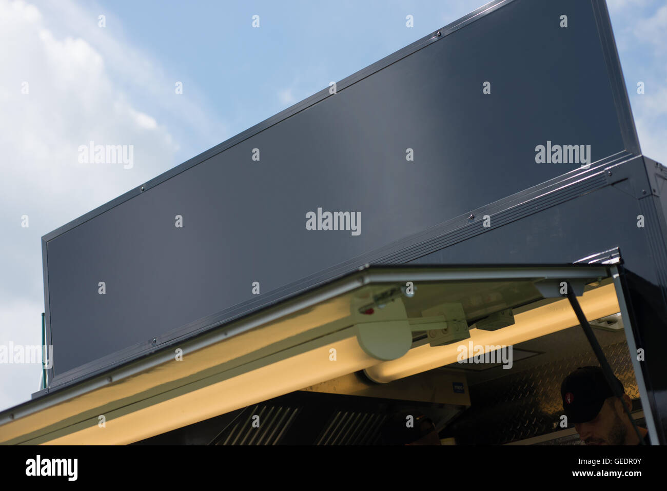 A grey empty or blank sign of a food cart outdoors with blue sky and ...
