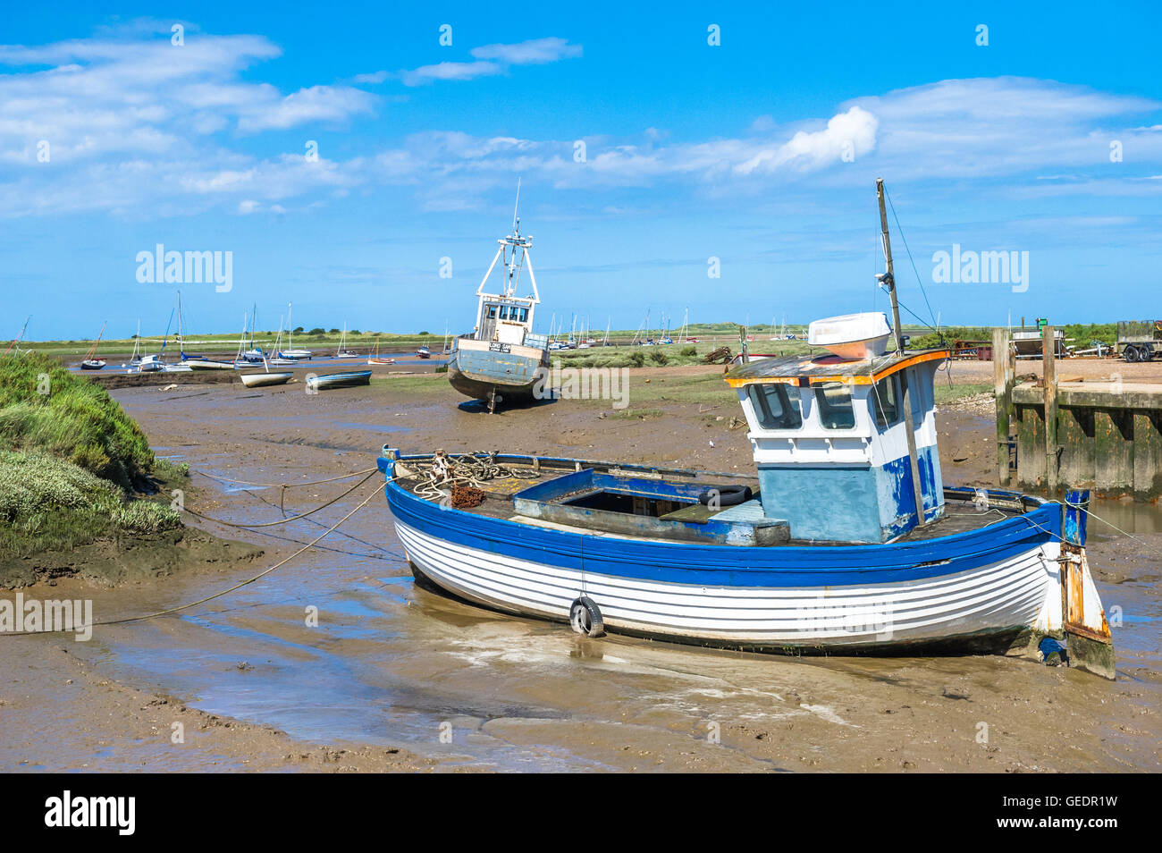 Small fishing boats beached at low tide in the mud at Brancaster ...