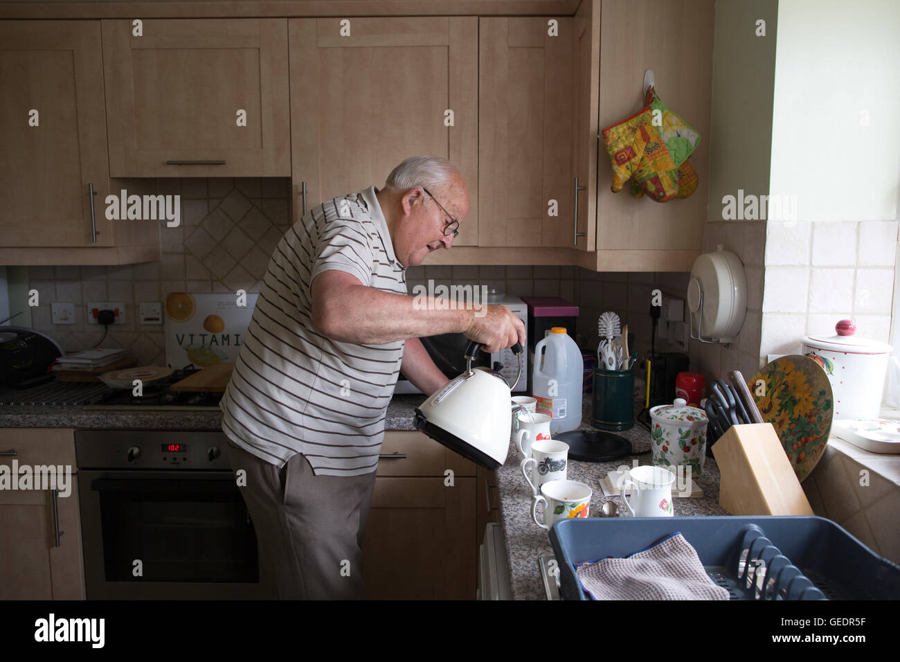 Old age pensioner making cups of tea for visitors in his kitchen at ...
