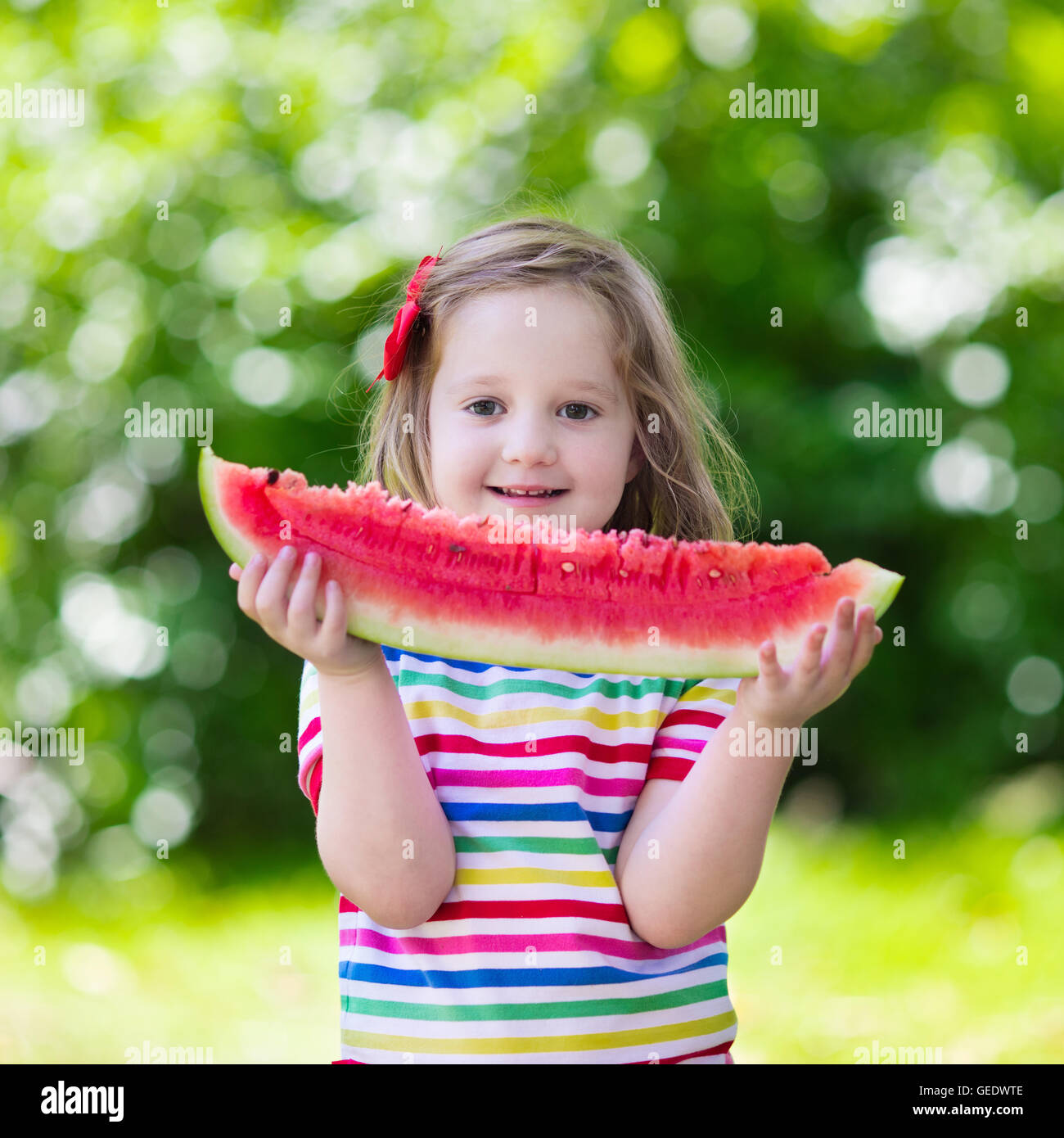 Child eating watermelon in the garden. Kids eat fruit outdoors. Healthy ...