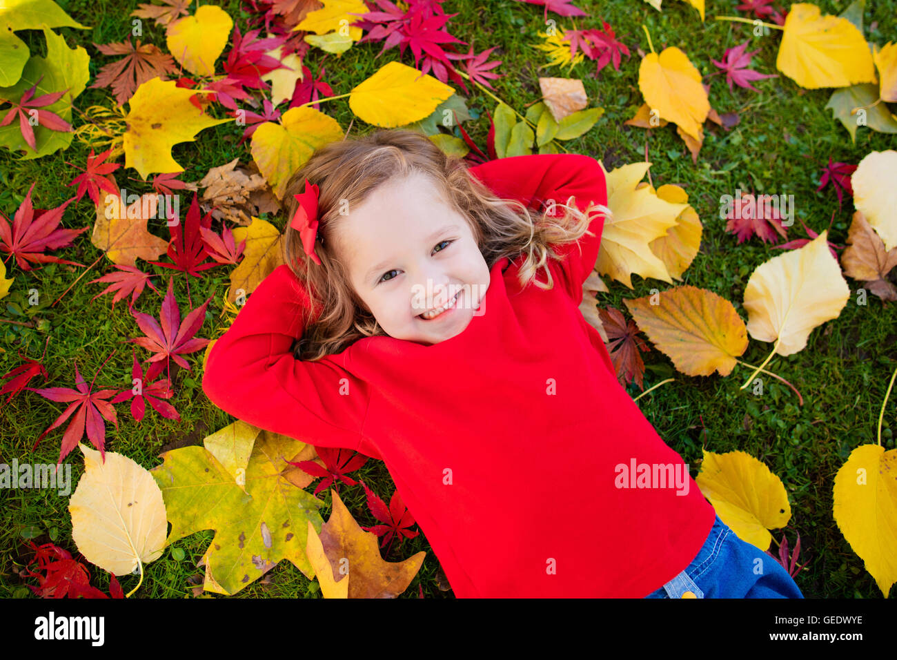 Happy little girl playing in beautiful autumn park on warm sunny fall ...