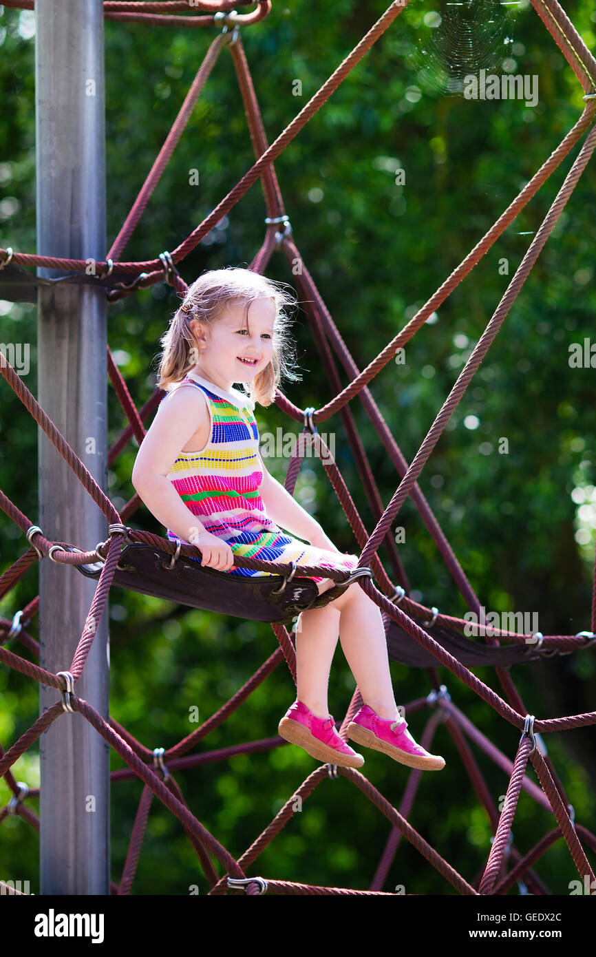 Active little child playing on climbing net and jumping on trampoline ...