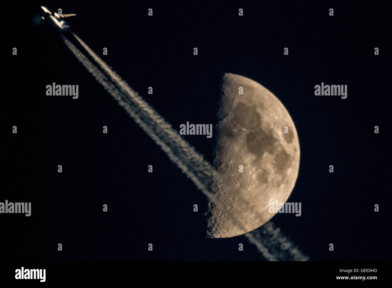 Jet's Contrail bisects moon Stock Photo - Alamy