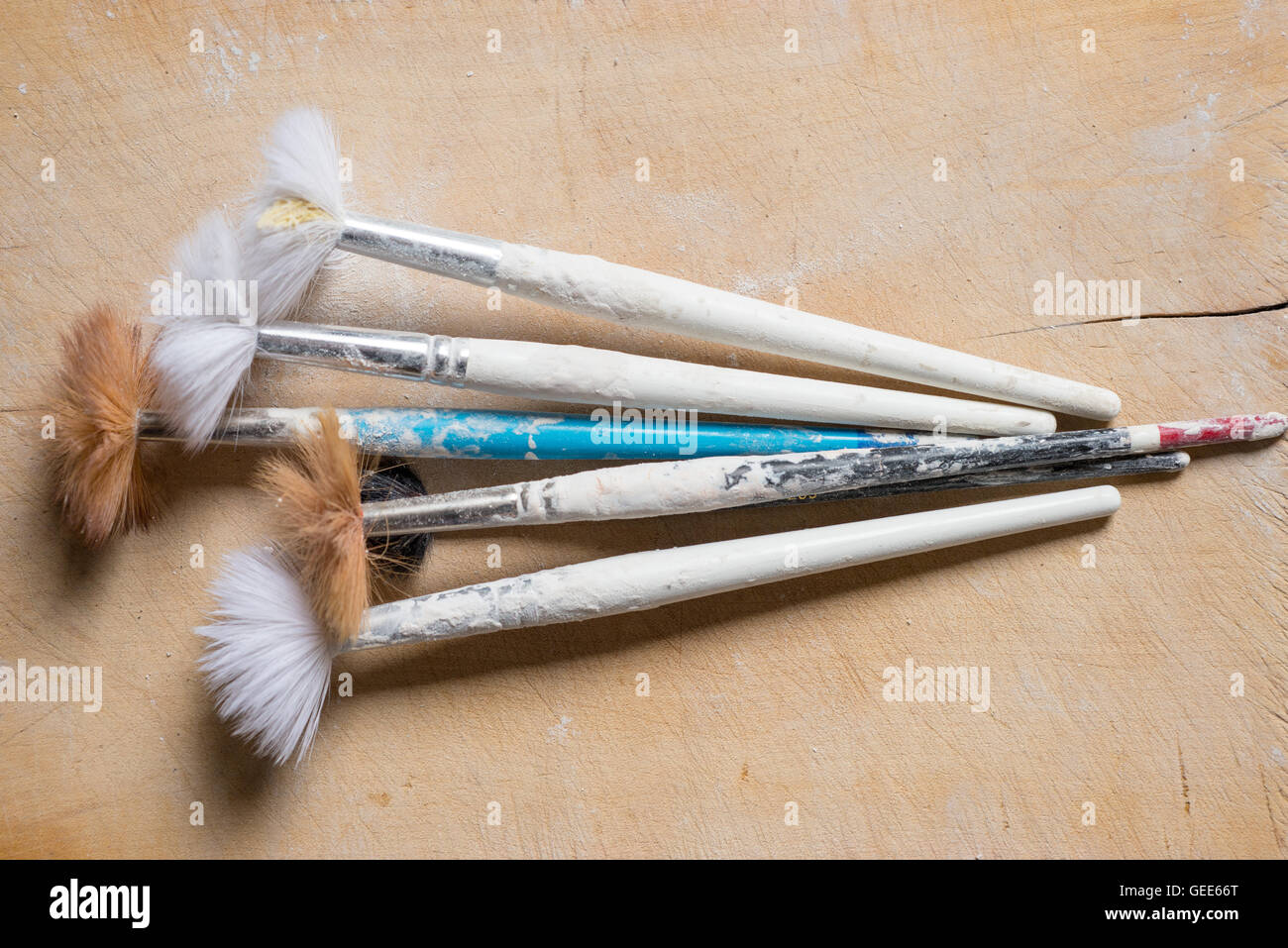 A set of used paintbrushes with plaster-splattered handles and split ...