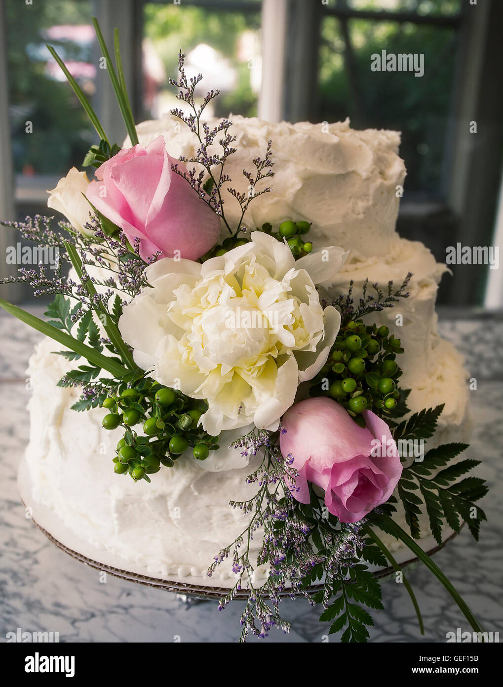 White wedding cake with white icing, roses, peonies, greenery Stock ...