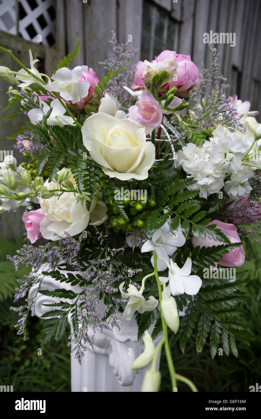 Flower arrangement sitting on white column in garden Stock Photo - Alamy