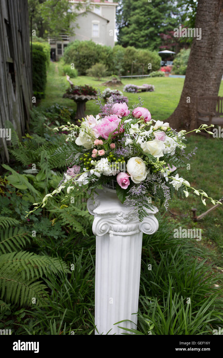 Flower arrangement sitting on white column in garden Stock Photo - Alamy
