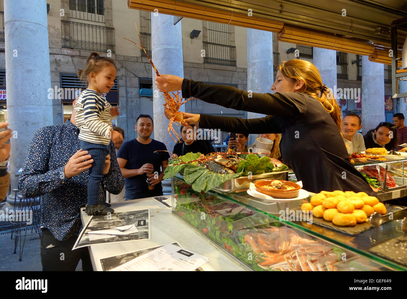 A little girl is entertained by a waitress with a lobster at a ...