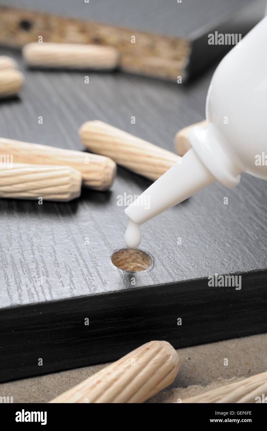 inserting glue to the hole on black particleboard Stock Photo - Alamy