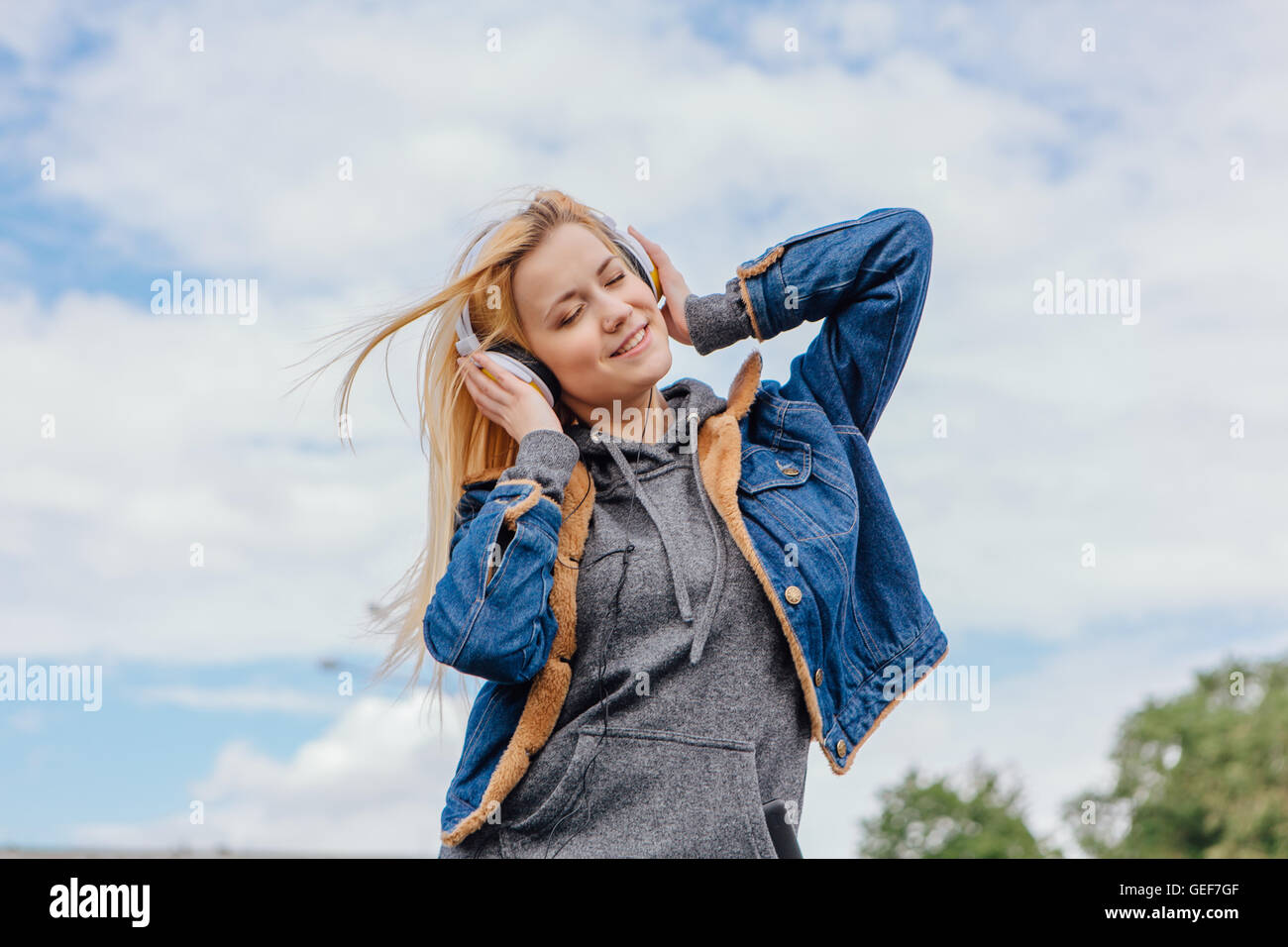 Girl listening to music streaming with headphones and dancing on sky ...
