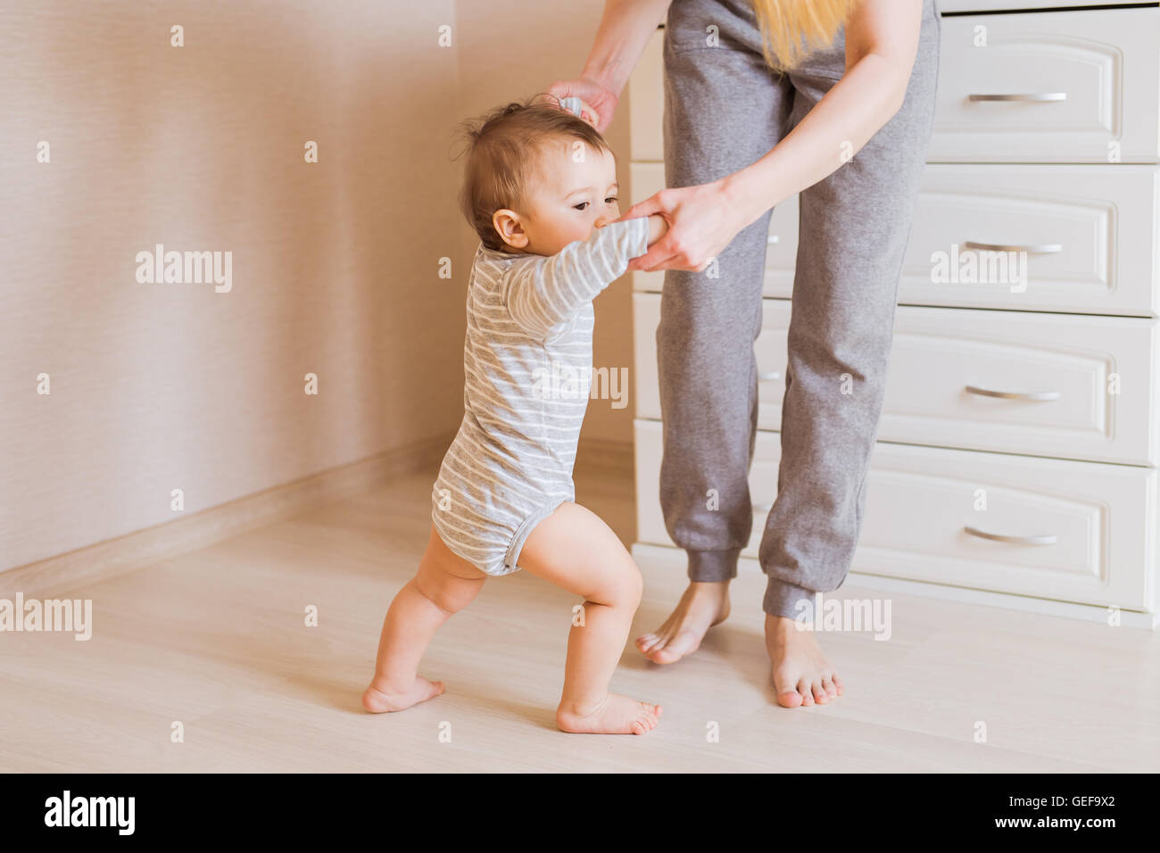 baby taking first steps with mother help Stock Photo - Alamy