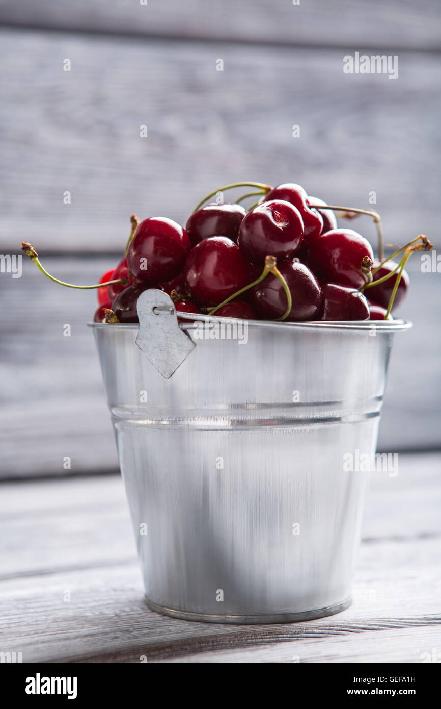 Bucket filled with cherries. Bucket on light gray surface. Fruit that ...