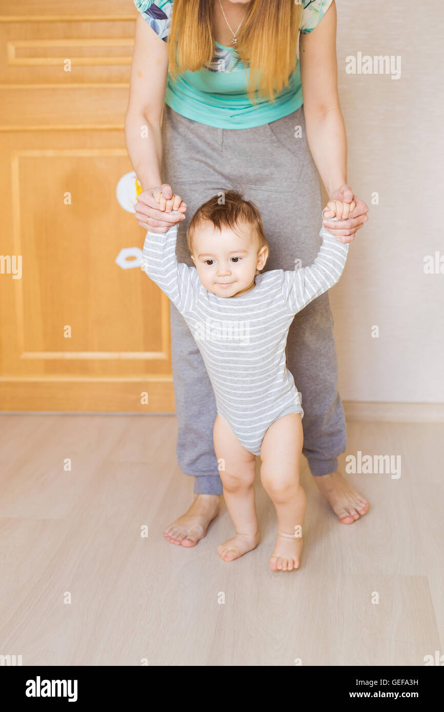 baby taking first steps with mother help Stock Photo - Alamy