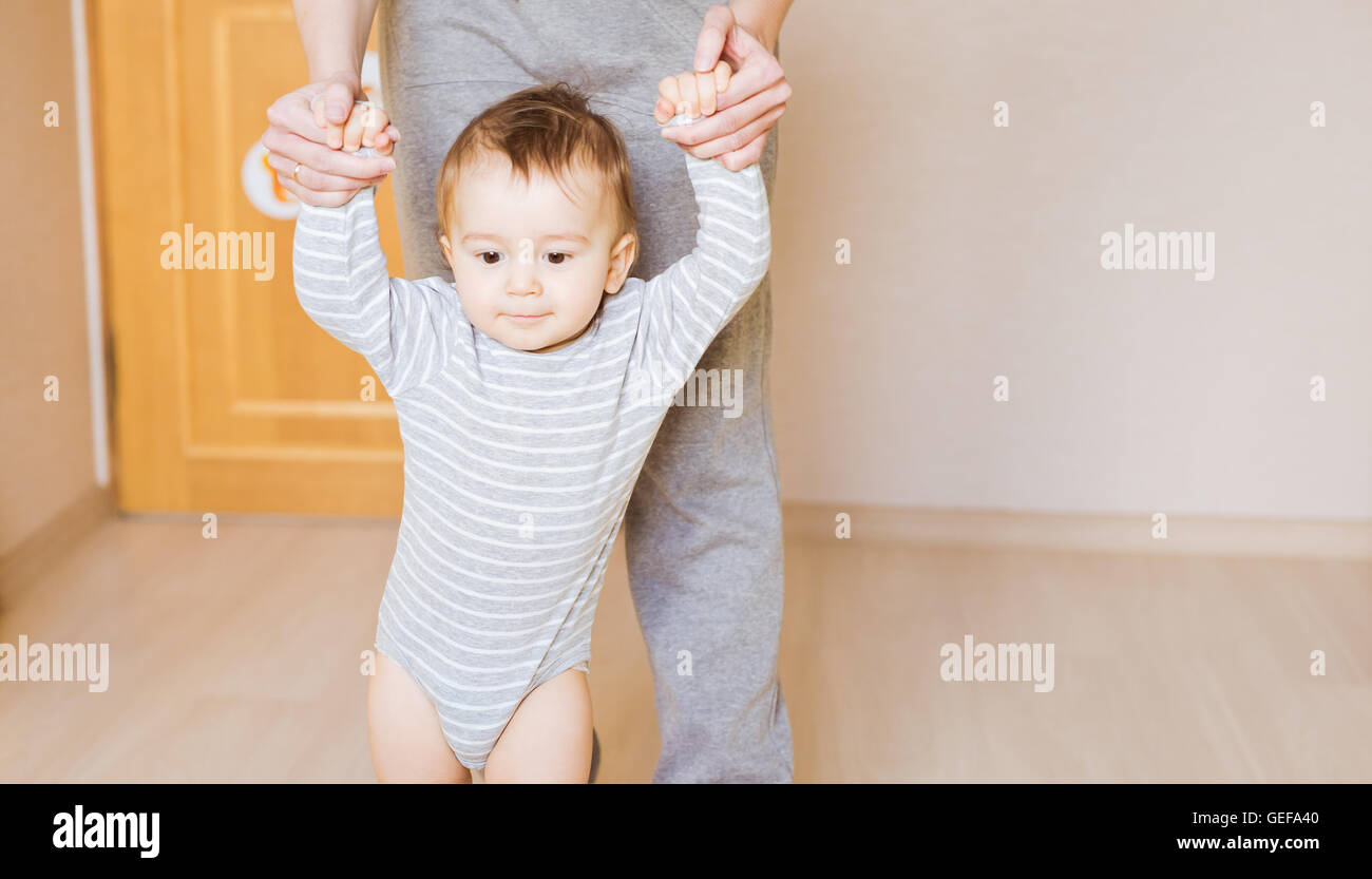 baby taking first steps with mother help Stock Photo - Alamy
