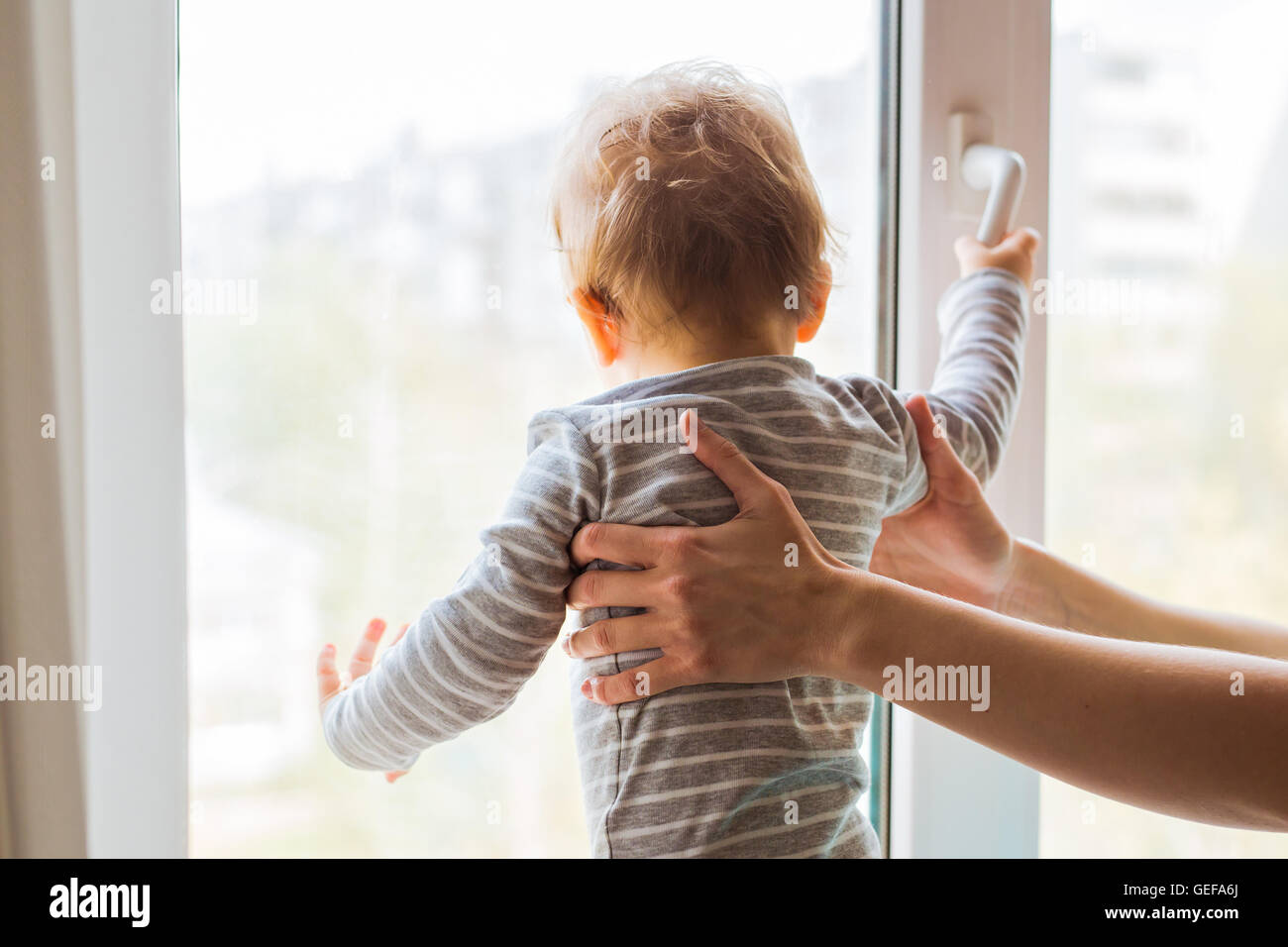 Cute baby boy looks in the window Stock Photo - Alamy