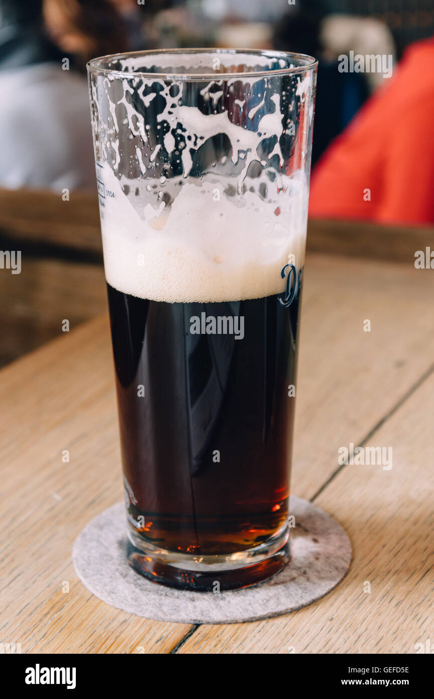 Glass of dark beer half-full in a restaurant interior Stock Photo - Alamy