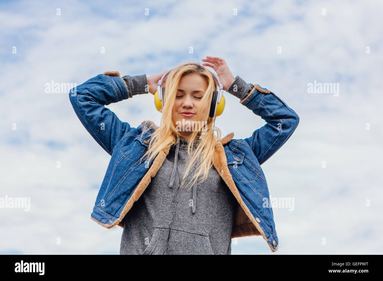 Girl listening to music streaming with headphones and dancing on sky ...