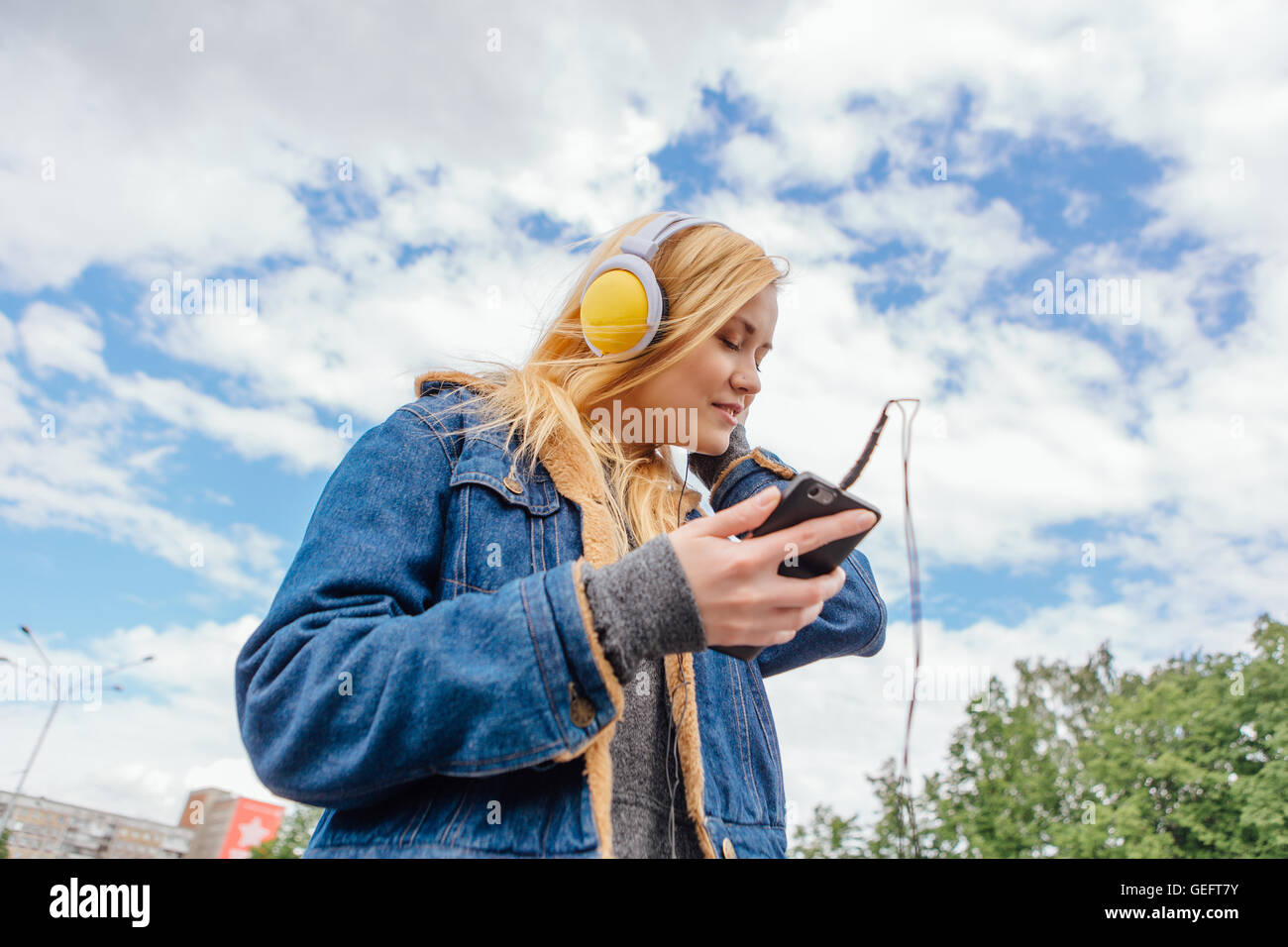 Girl listening to music streaming with headphones and dancing on sky ...
