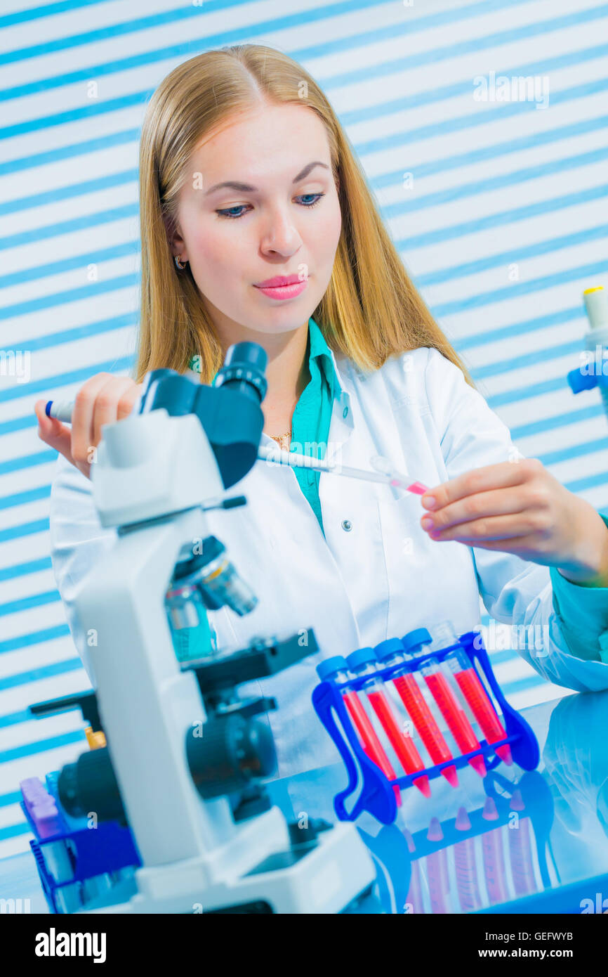 Laboratory assistant with long blonde hair fills microtubes for DNA ...