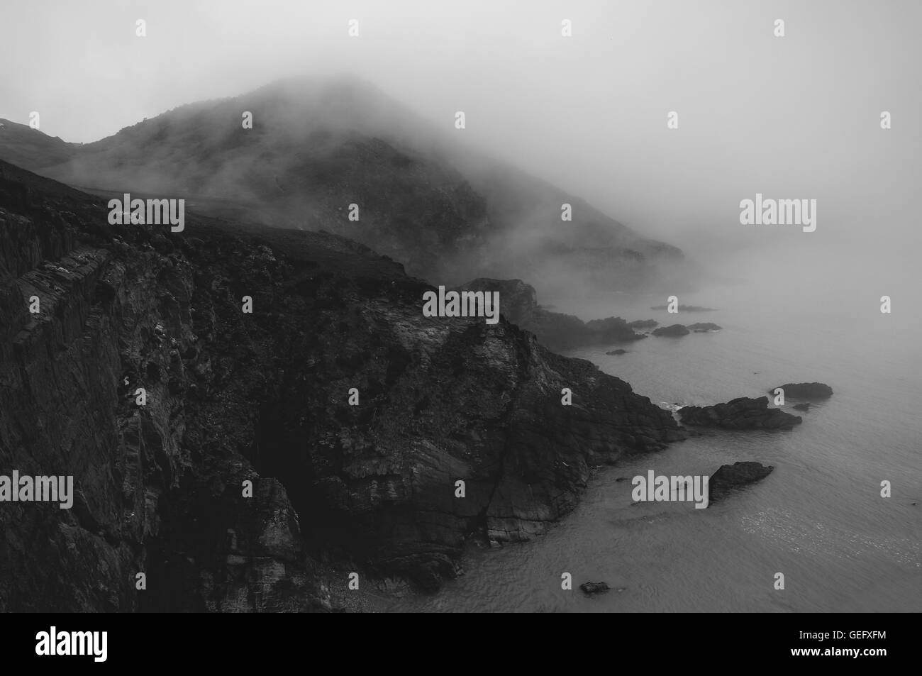 Mist rolling over coastal cliffs. Shot in black and white Stock Photo ...