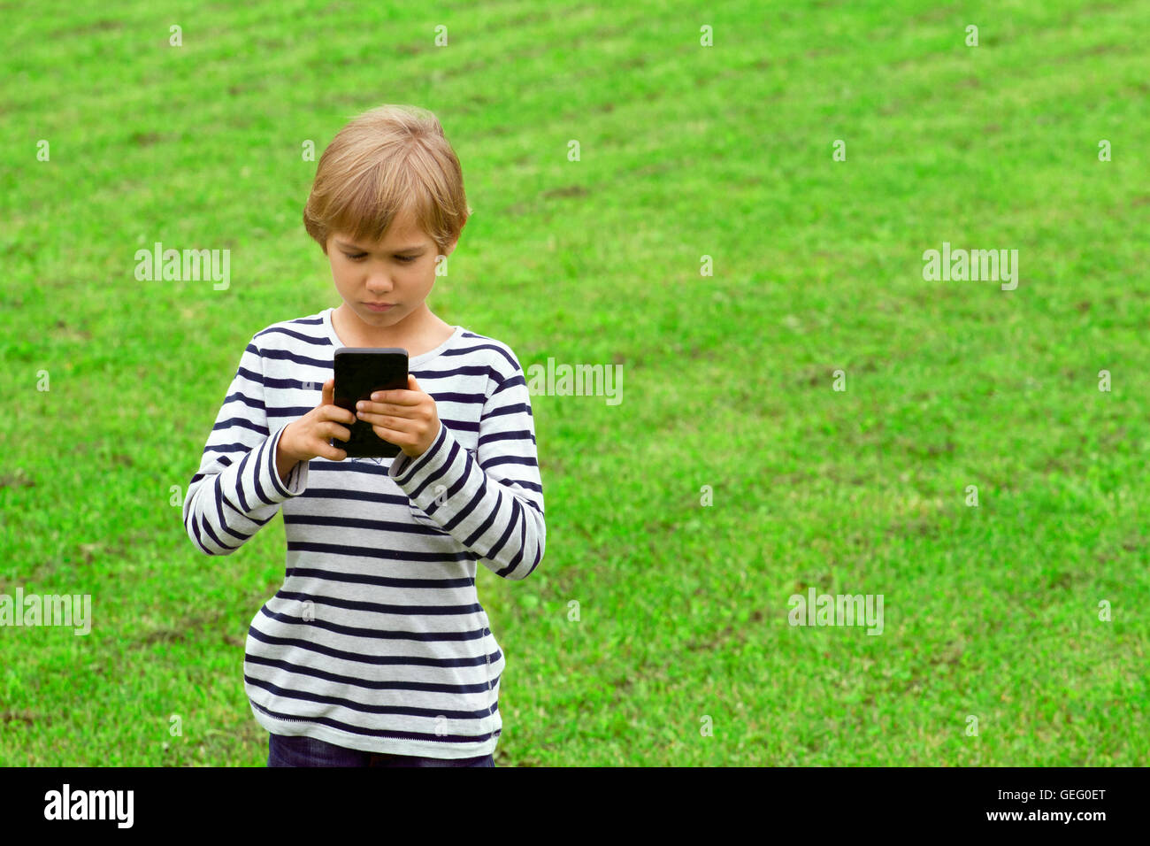 Boy with mobile phone outdoor. Child looking at the screen, playing ...