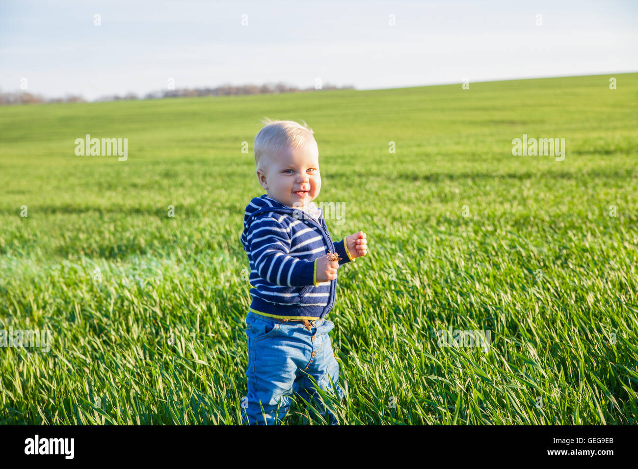 Beautiful baby boy standing in the green grass Stock Photo - Alamy