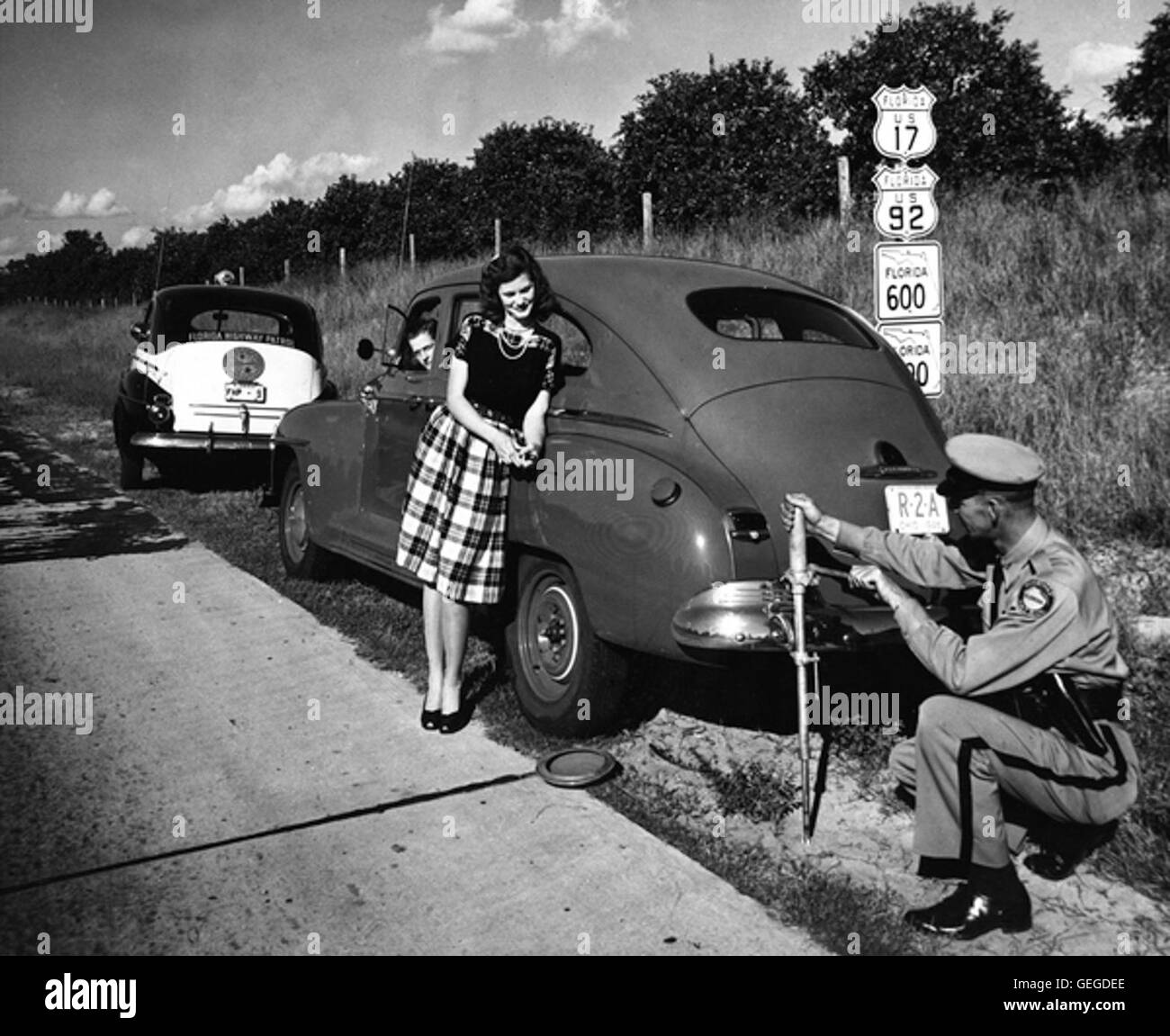 A Florida Highway Patrolman is shown changing a tire on the side of the ...