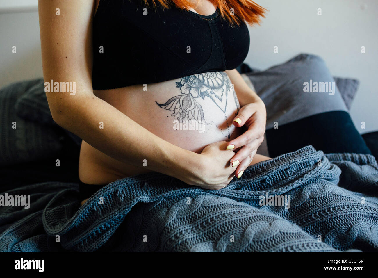 young pregnant woman posing for the camera, belly from close angle ...