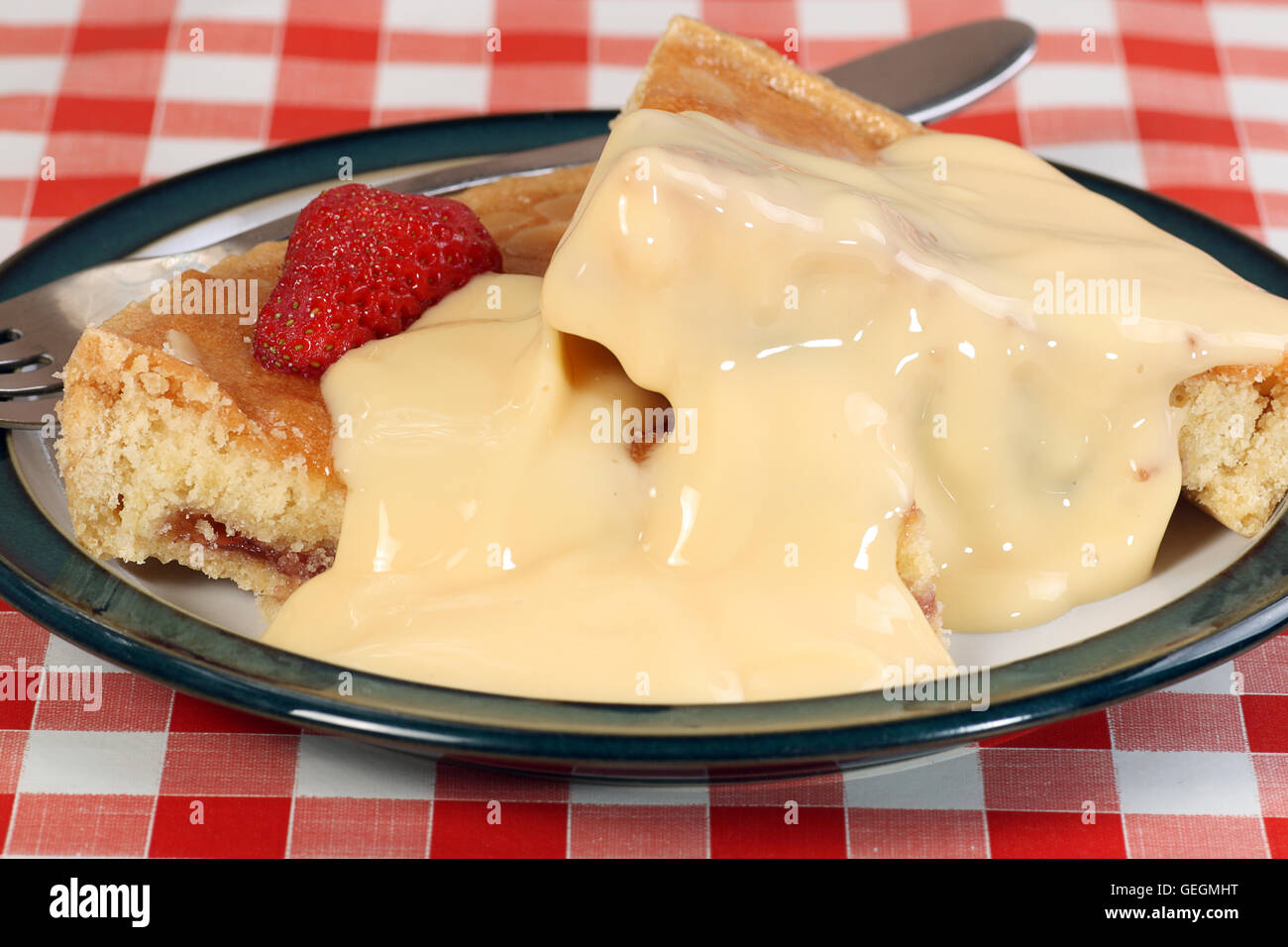 slice of bakewell pudding with strawberries and custard Stock Photo - Alamy