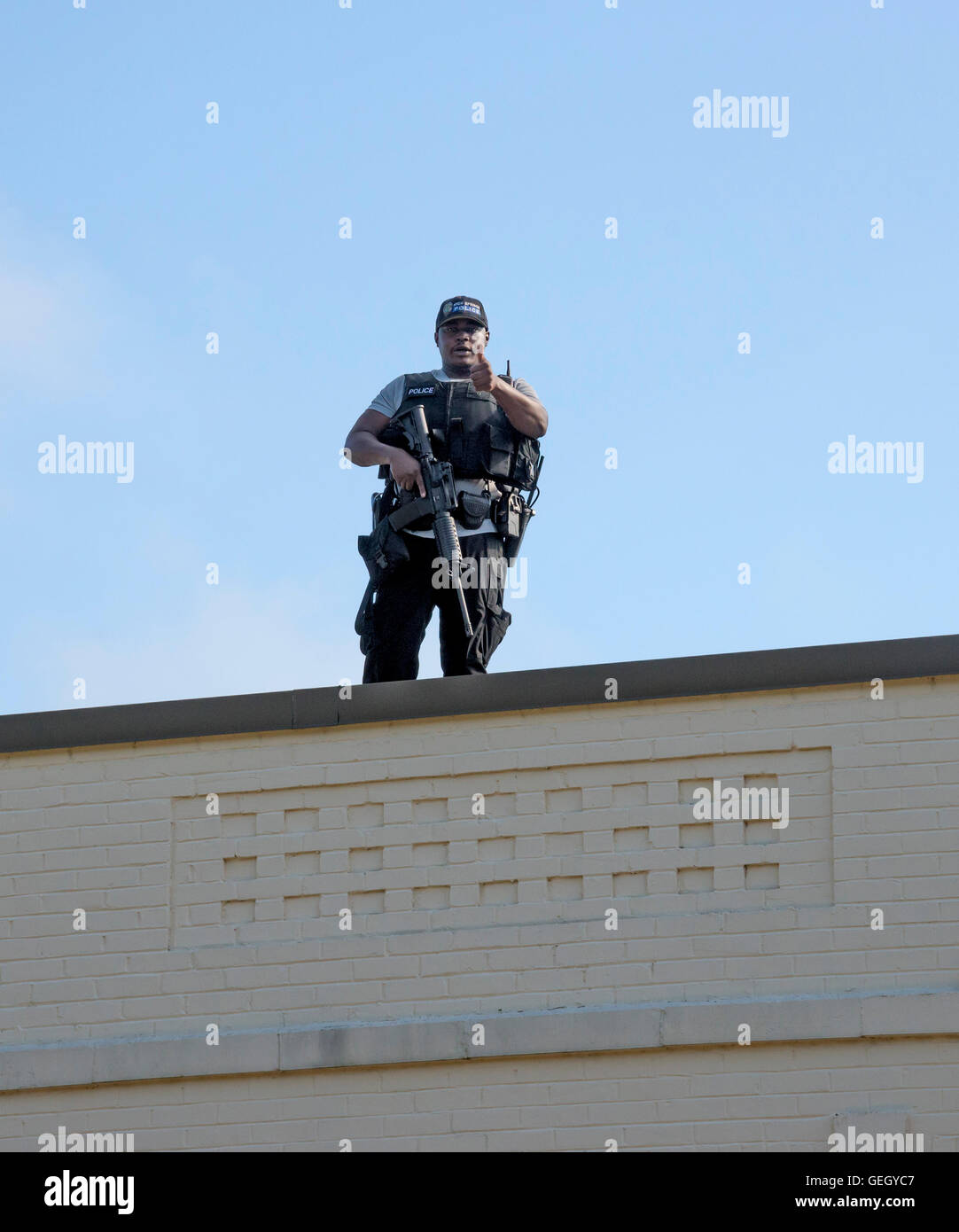 African American police officer in tactical gear watches over a police ...