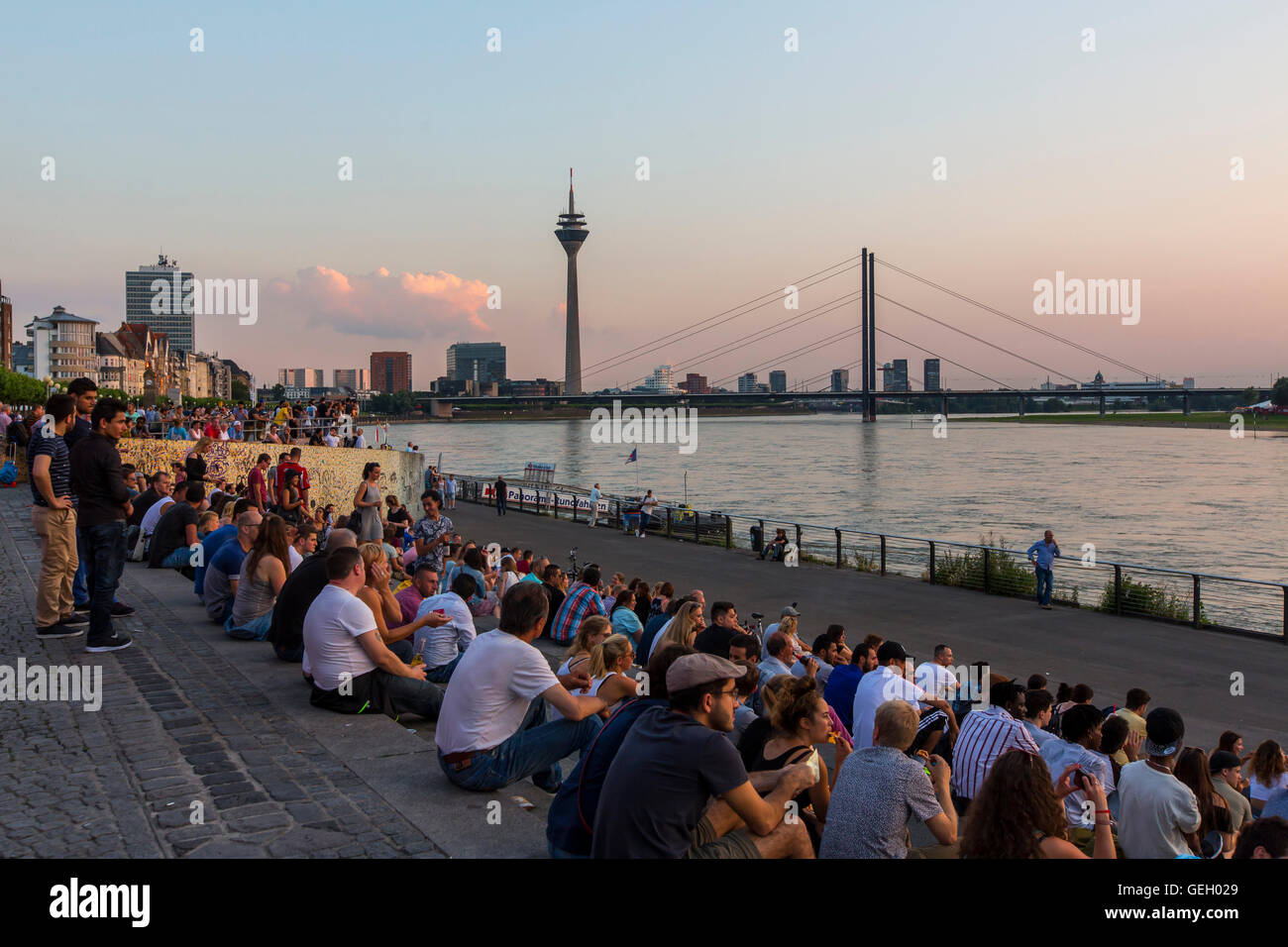 People sitting along river Rhine, on a warm summer evening, in the old ...
