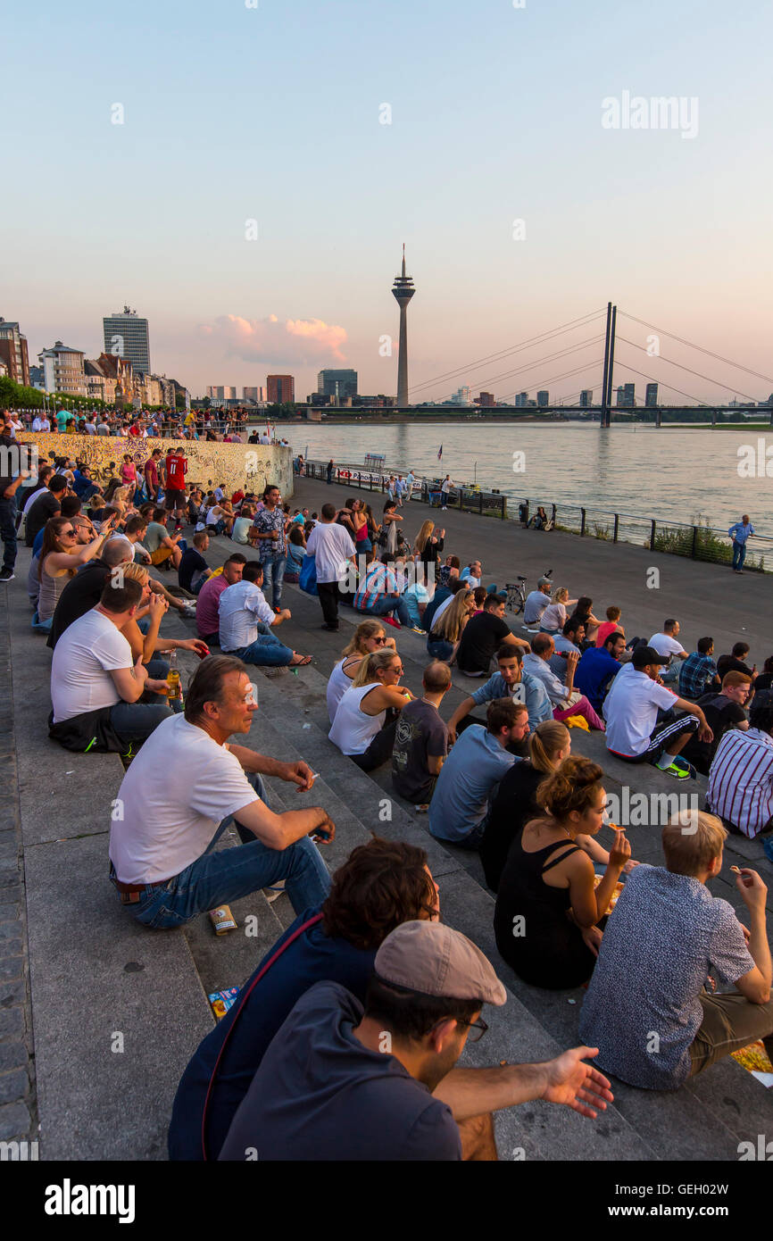 People sitting along river Rhine, on a warm summer evening, in the old ...