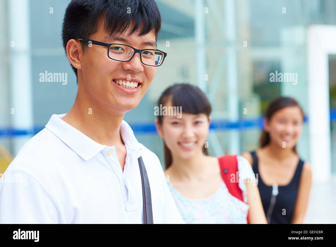 three happy young Chinese or asian college students looking at camera ...