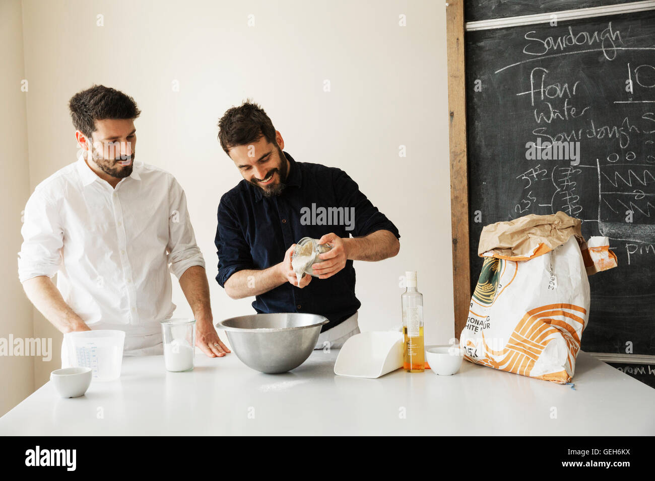 Two bakers standing at a table, preparing bread dough, baking ...