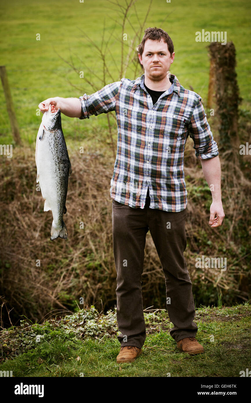A man standing holding a large freshly caught salmon fish Stock Photo ...