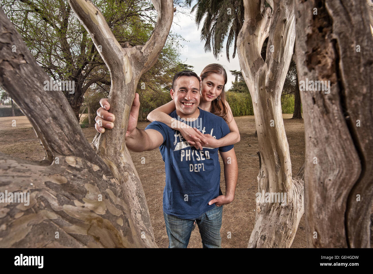 Couple embracing pose next to tree branches Stock Photo - Alamy