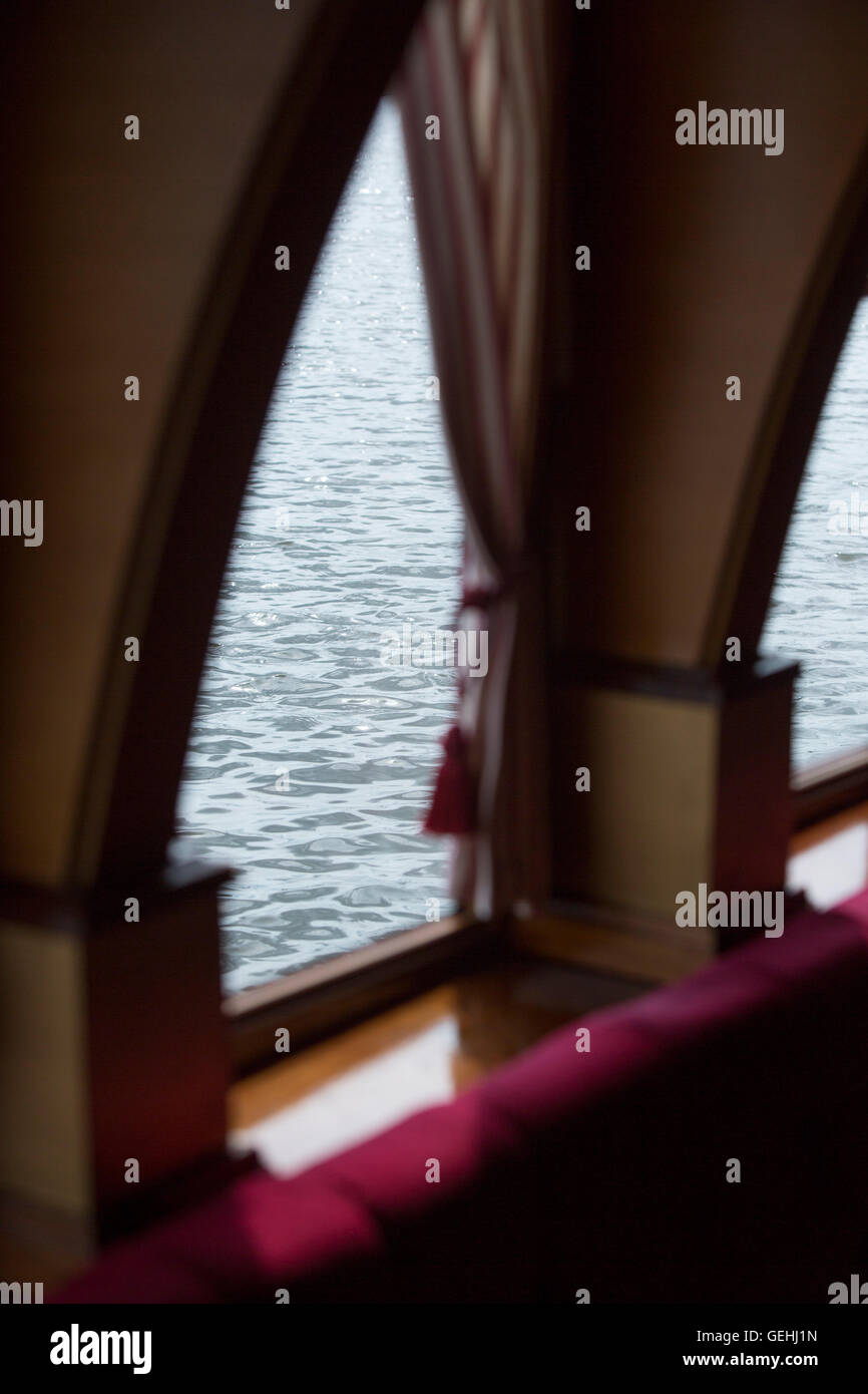 Looking out through a small window with curtain on a boat to the river ...