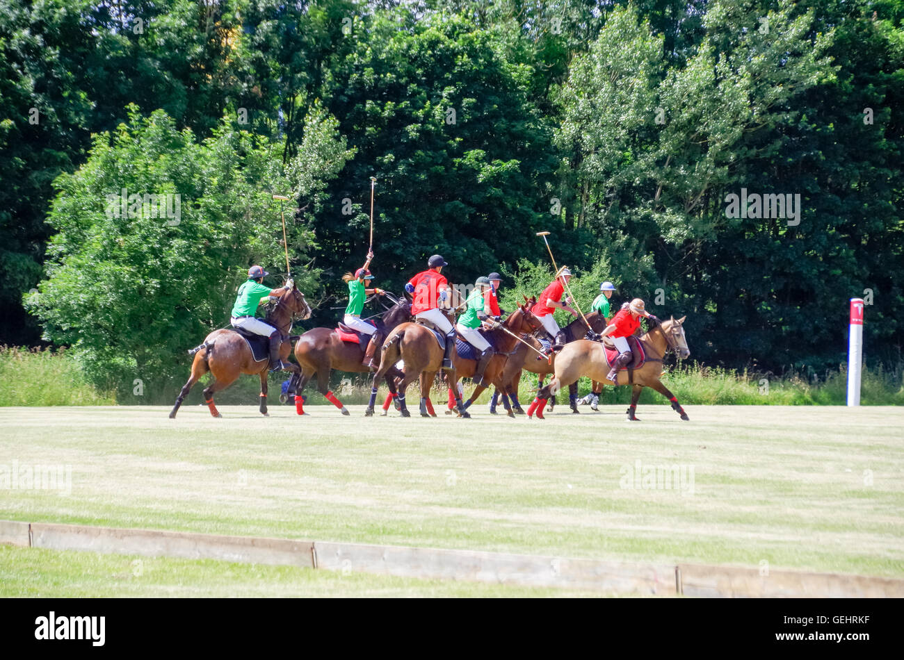 Polo players in green and red shirts playing near the goal poles during ...