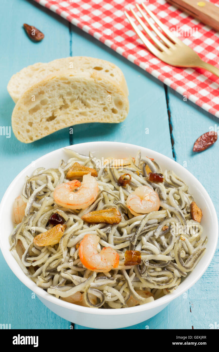 Surimi elvers with prawns, garlic and pepper on a white bowl, bread ...