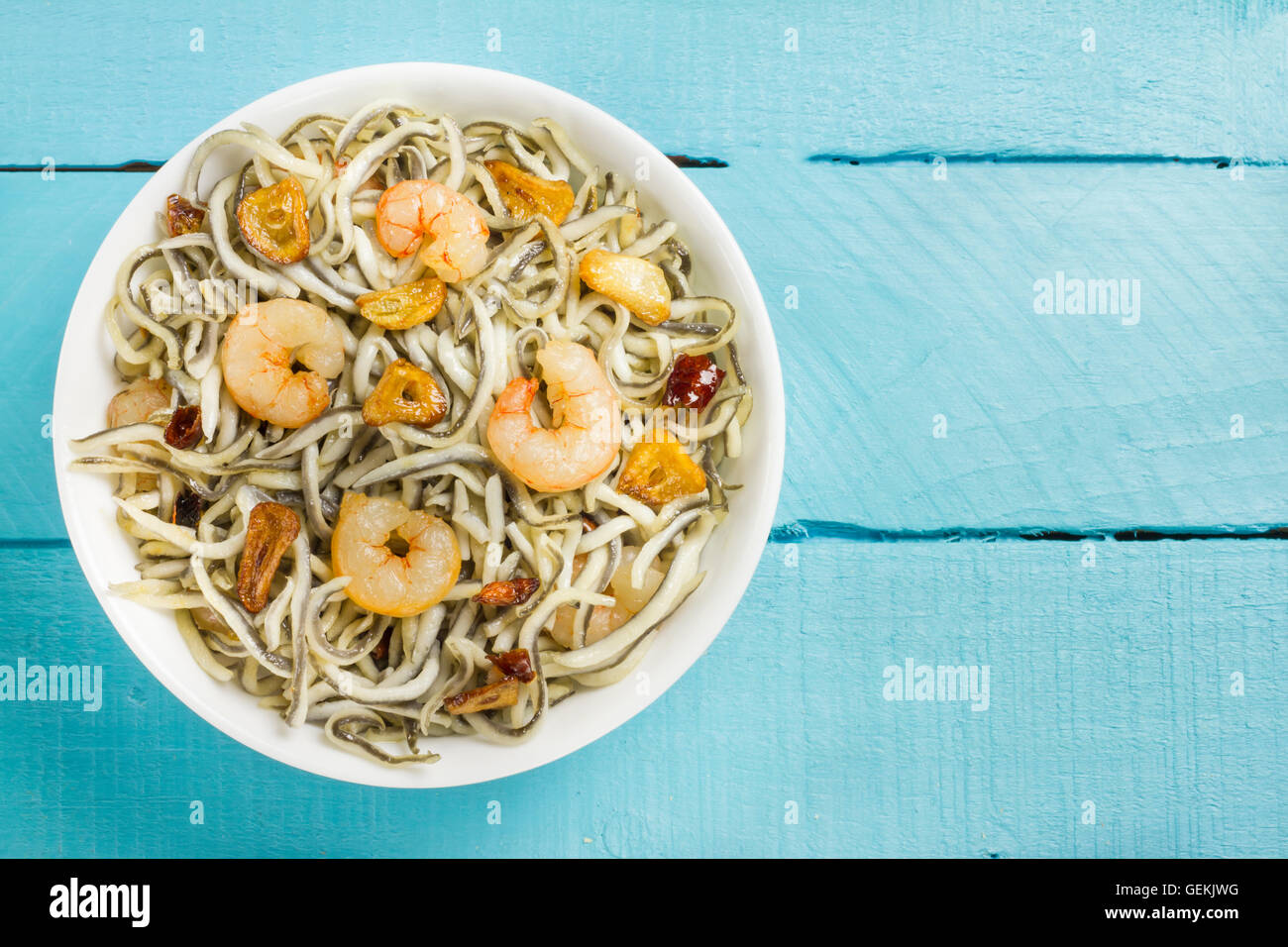 Surimi elvers with prawns, garlic, and pepper on a blue wooden table ...