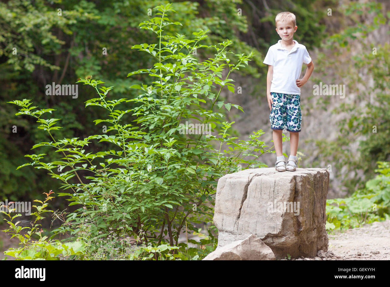 Little smiling boy standing on a big stone Stock Photo - Alamy