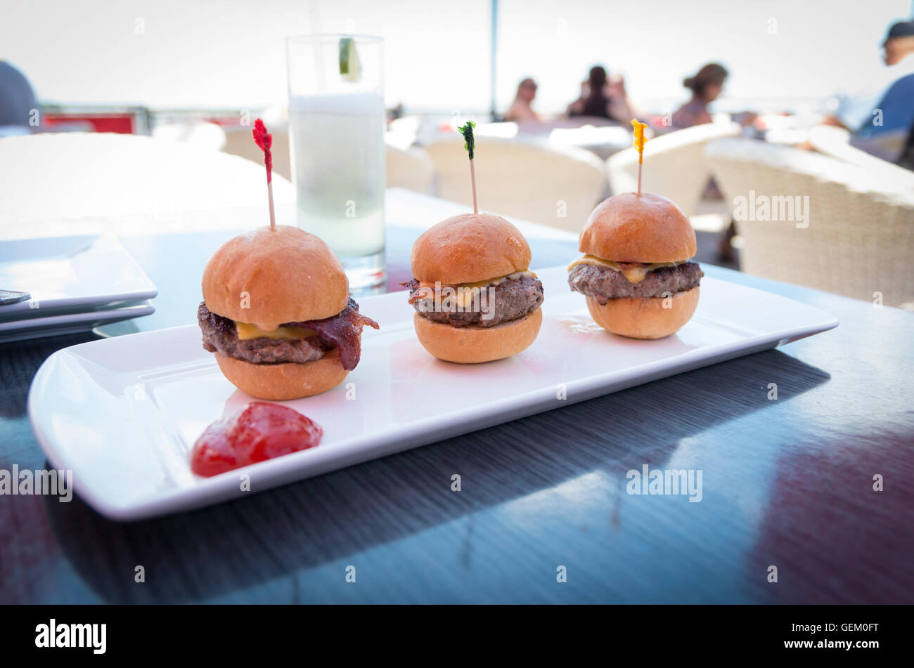 Three sliders (mini bacon cheeseburgers) on rectangular plate in ...