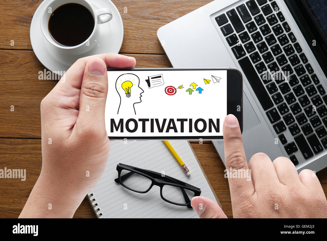 MOTIVATION message on hand holding to touch a phone, top view, table ...