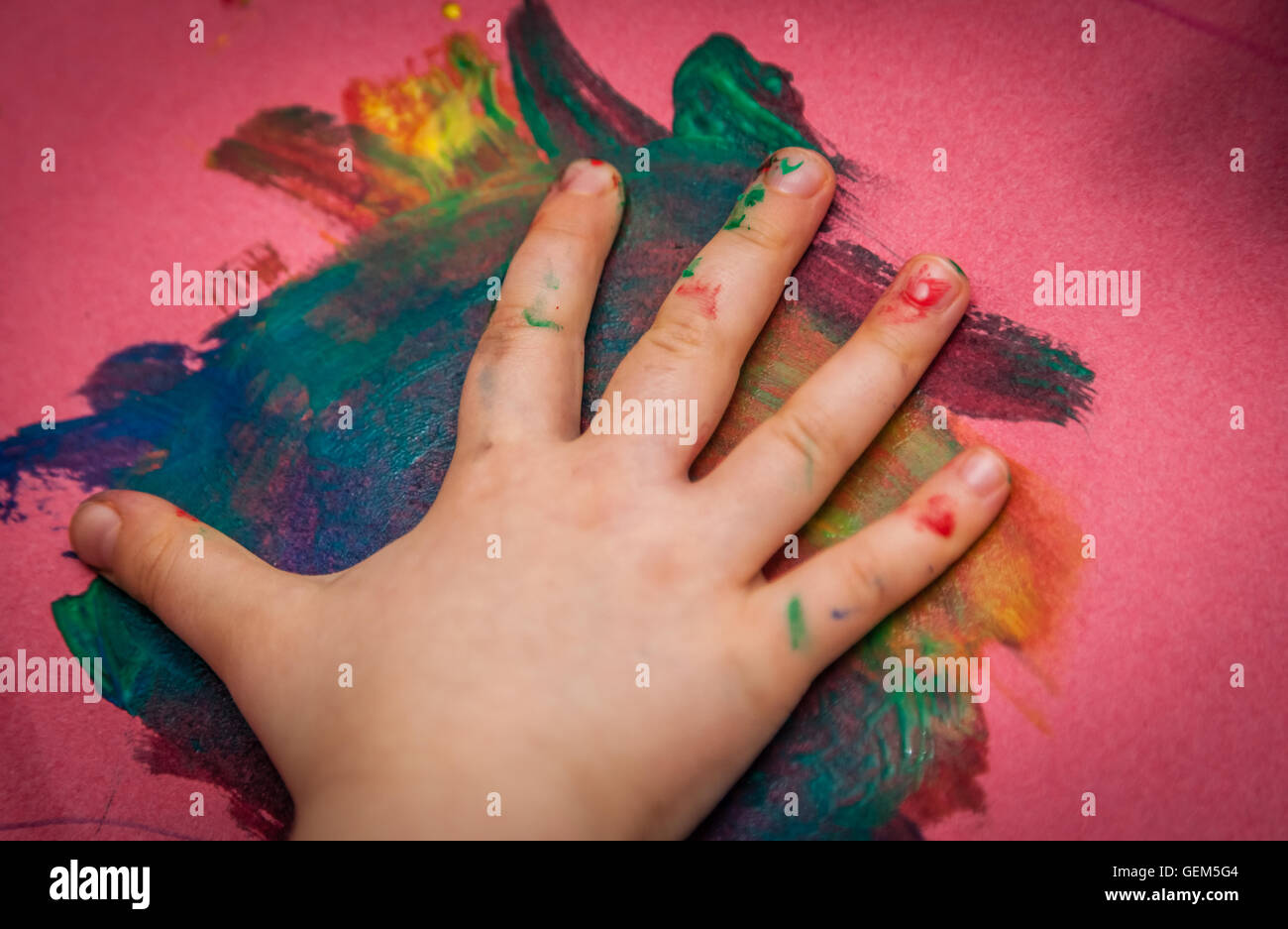 Child hand making colorful marks on a paper with a watercolor paint ...