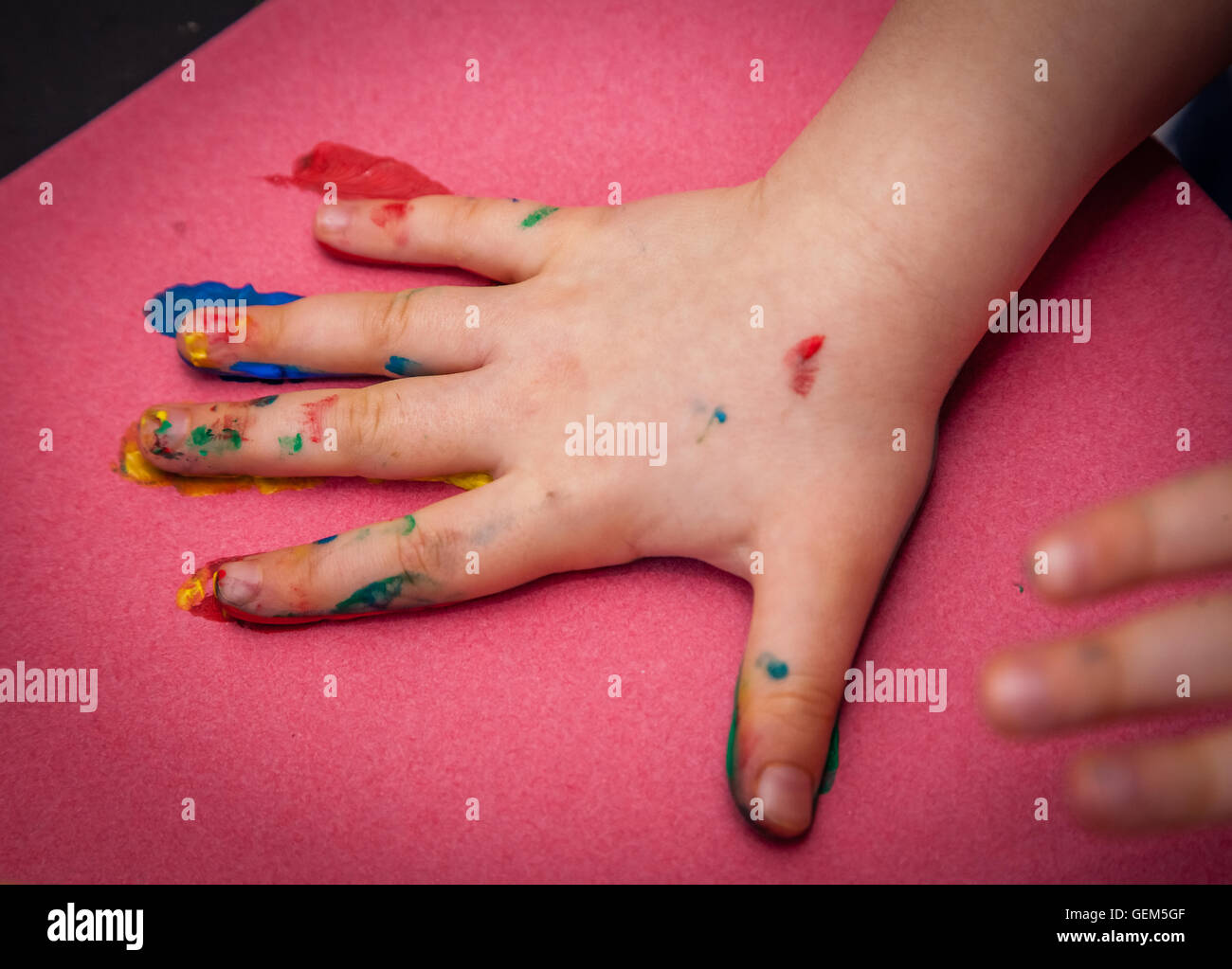 Child hand making colorful marks on a paper with a watercolor paint ...