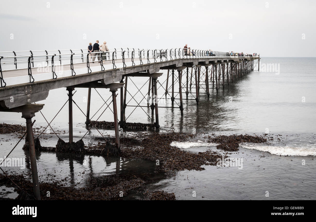 People walking on Saltburn`s Victorian pier with seaweed washing in at ...