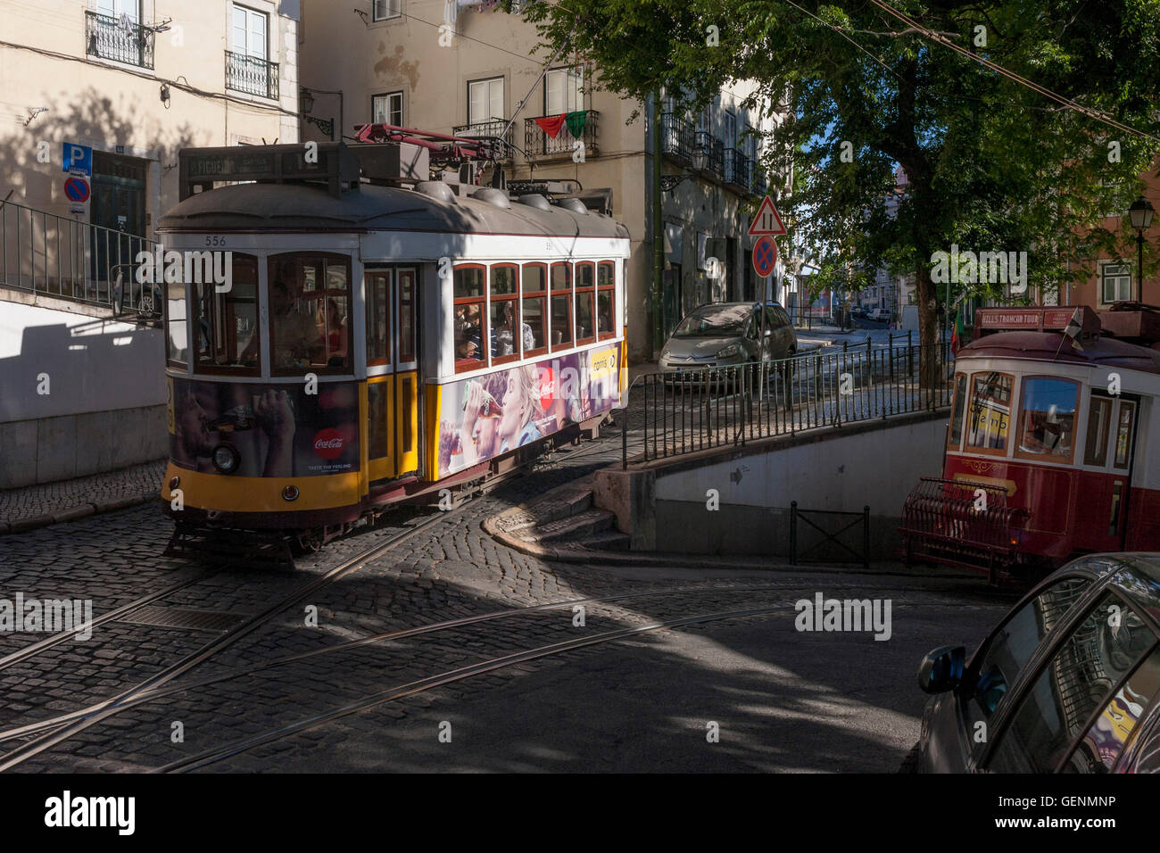 Tram lines merge on a narrow cobbled street shared by cars in Lisbon ...