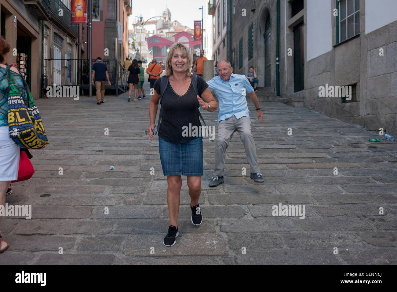 Middle-aged couple mess about with a backwards running race on a hill ...
