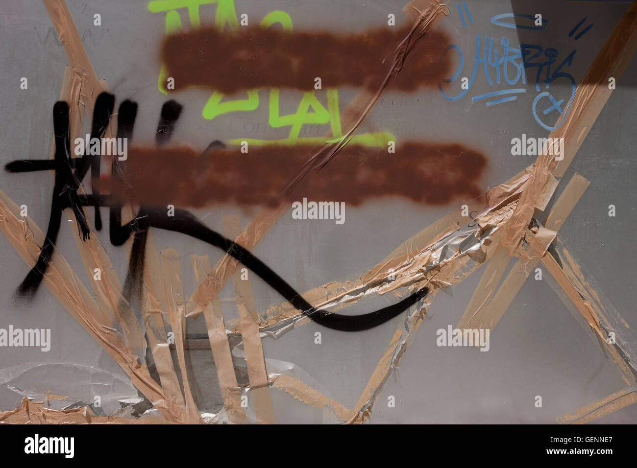 Taped-up glass and sprayed graffiti on a shop front window in Porto ...