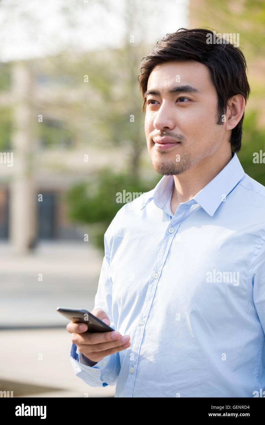 Young Chinese man holding a smart phone Stock Photo - Alamy